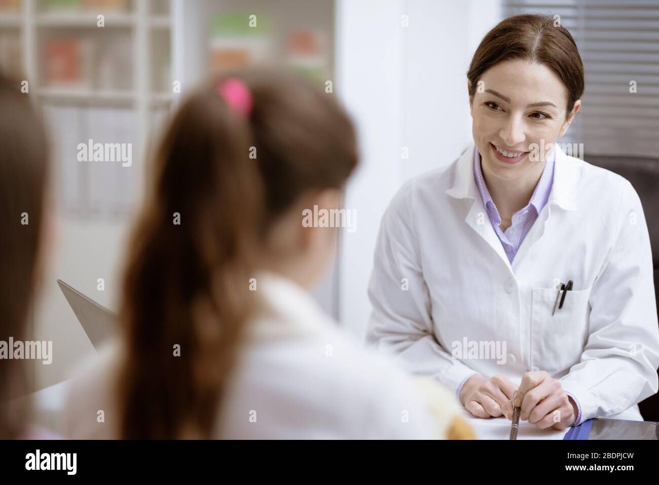 Female doctor sitting at desk and meeting patients in the office, she ...