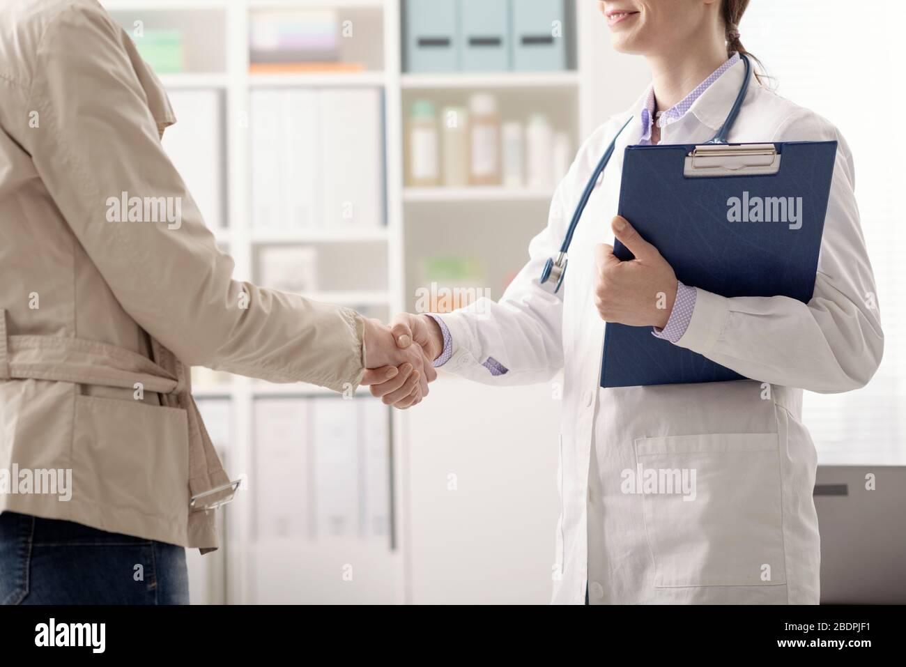 Female patient meeting the doctor in the office, they are shaking hands ...