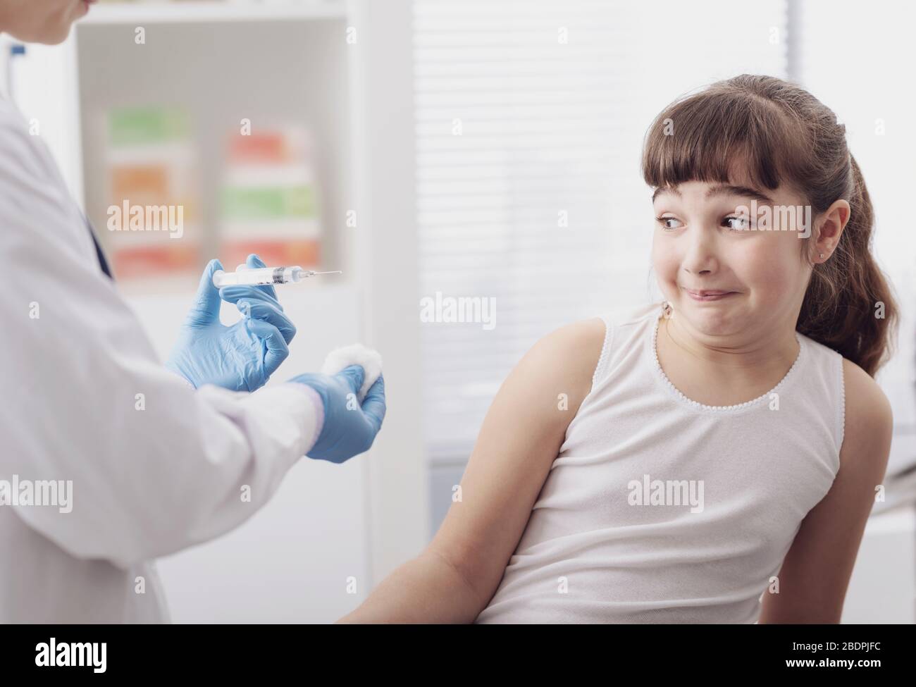 Doctor giving an injection to a scared child, the girl is frightened ...