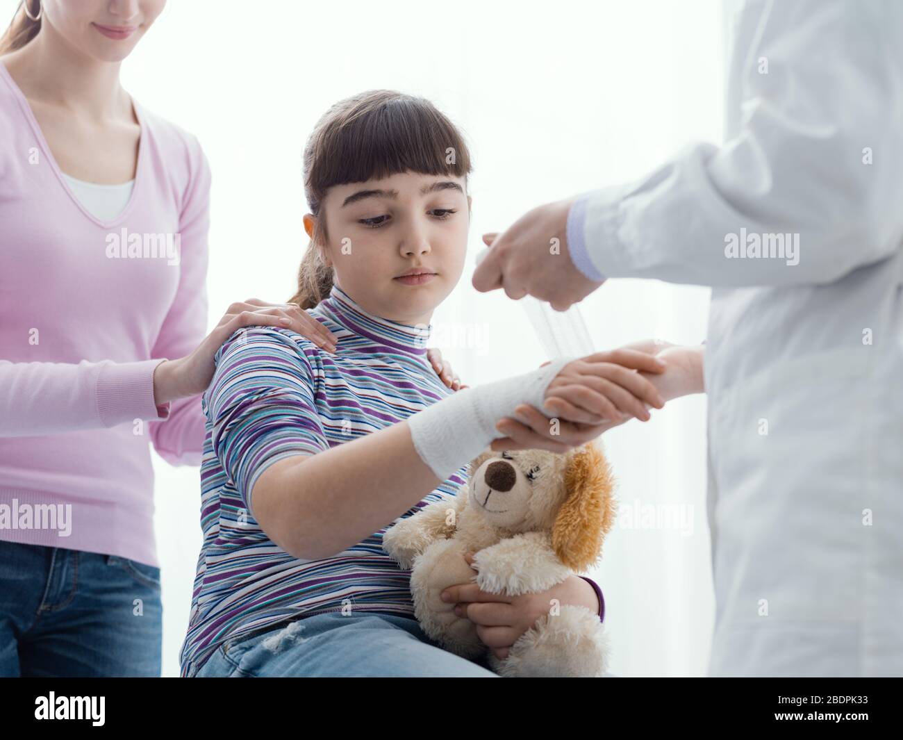 Doctor wrapping a girl's injured wrist with gauze and bandage, the ...