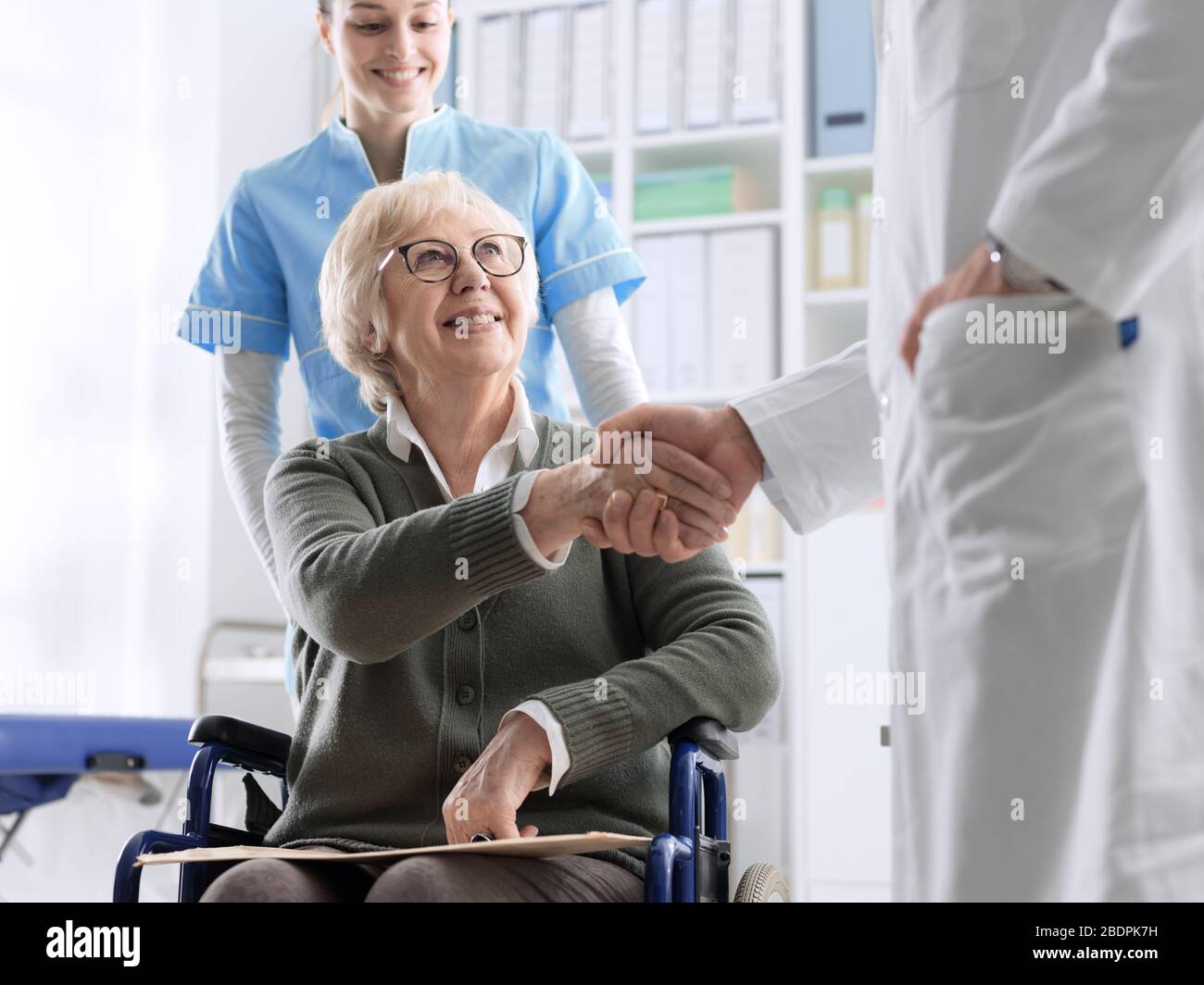 Doctor giving an handshake to a smiling senior female patient and ...
