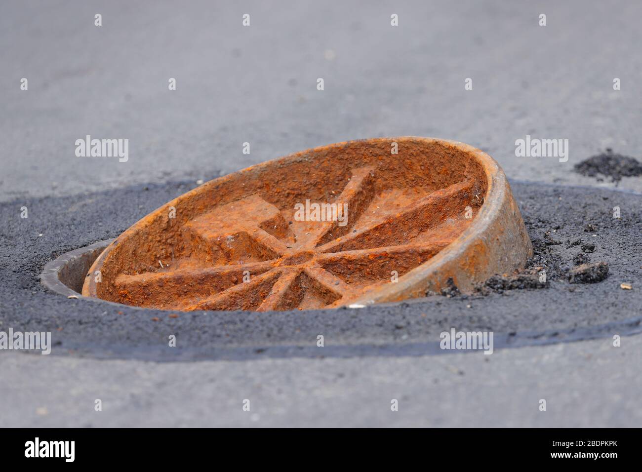 A raised manhole poses a danger to motorists Stock Photo - Alamy