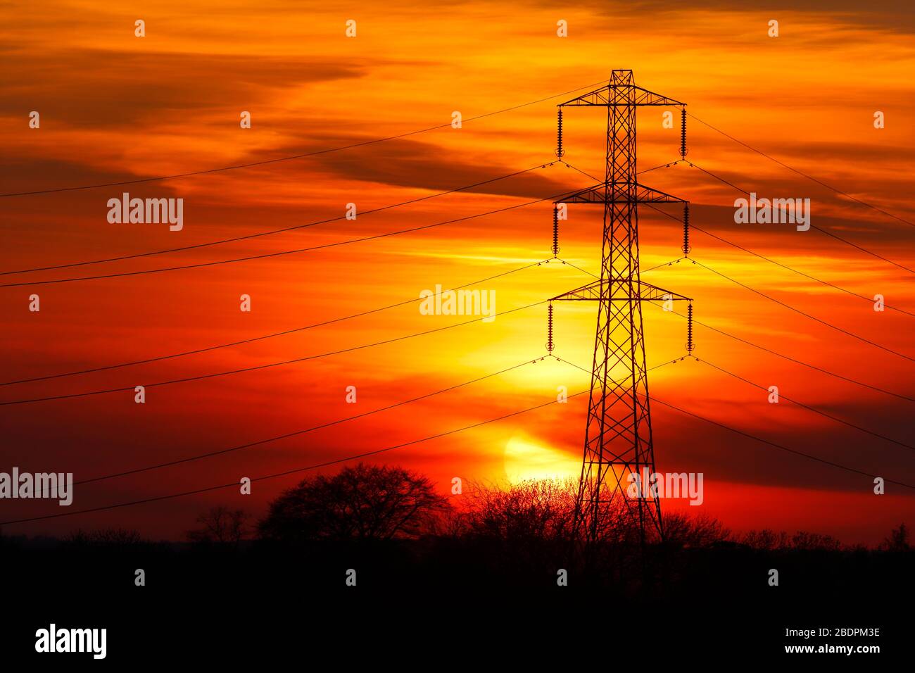An electricity pylon silhouetted against the setting sun in Swillington ...