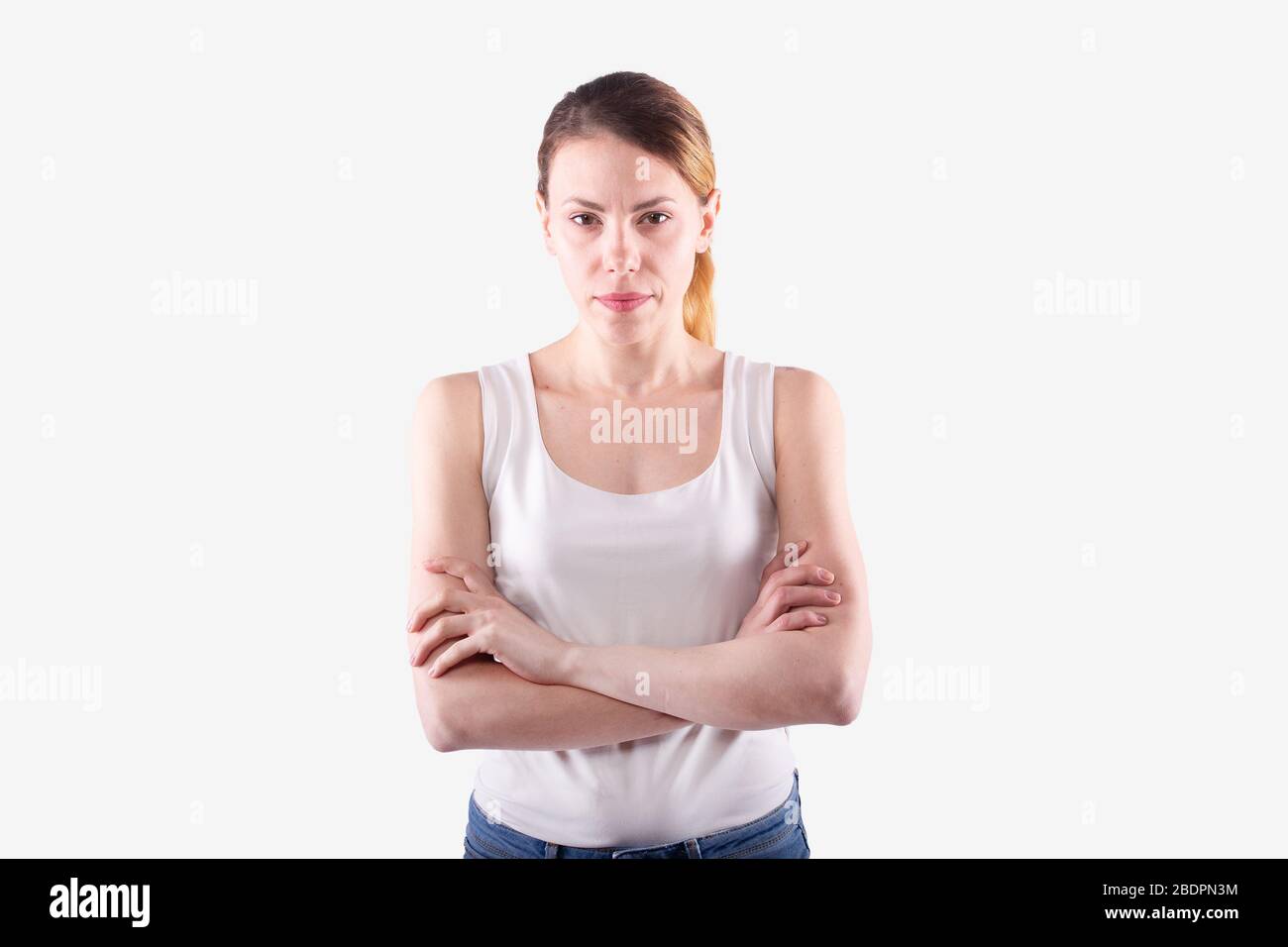 Lean physique woman looks seriously, stands with arms crossed. White ...