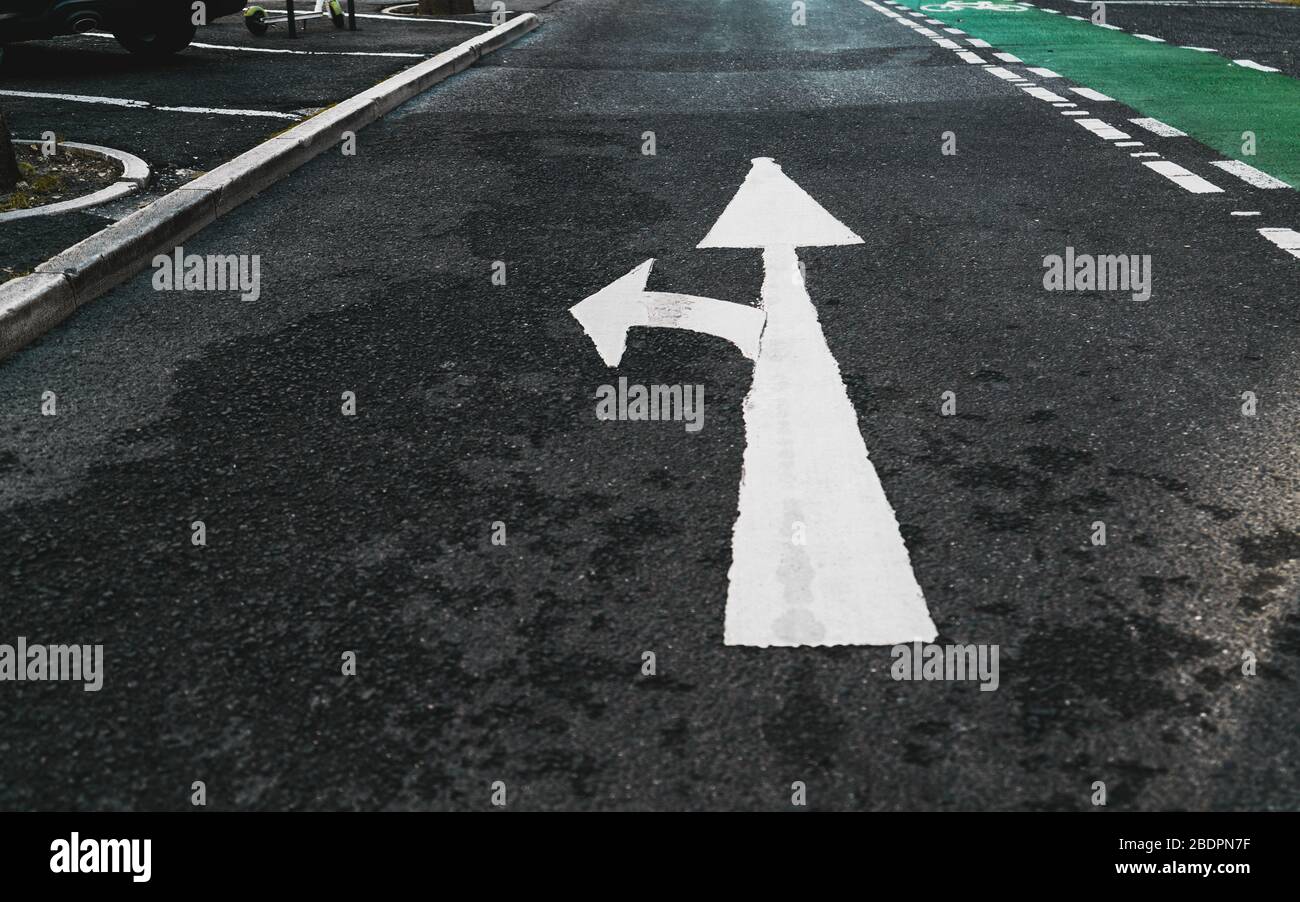 Road marking on the asphalt: white paint branch arrow pointing forward ...