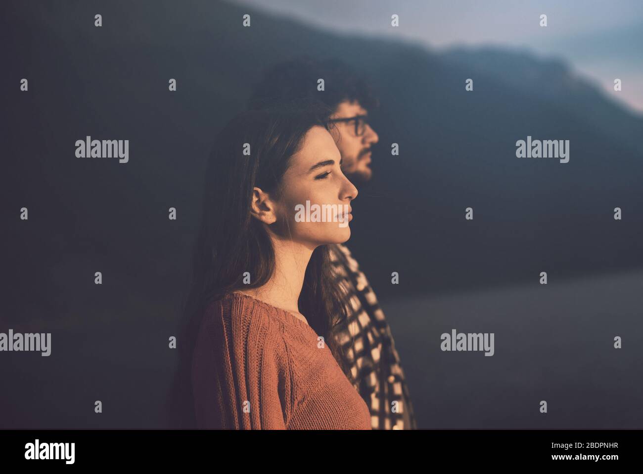 Young couple standing together and looking at the sunset outdoors Stock ...