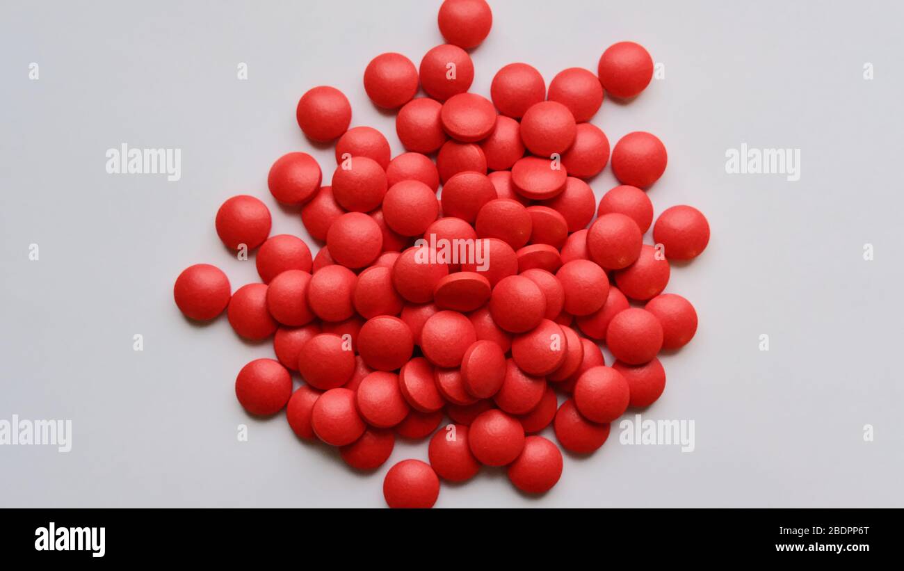 A scattered pile of red round frosted pills on a white background Stock ...