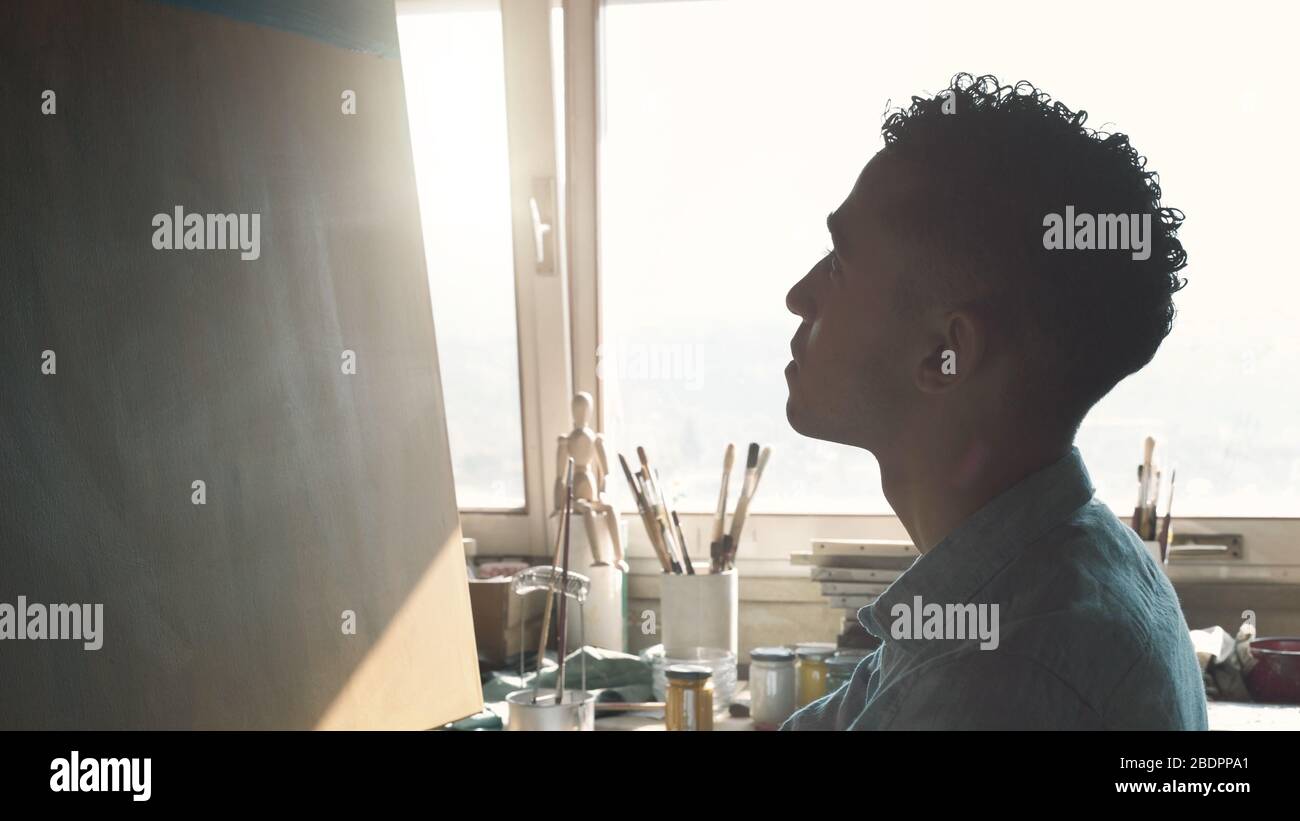 Young creative artist looking at his painting and thinking Stock Photo ...