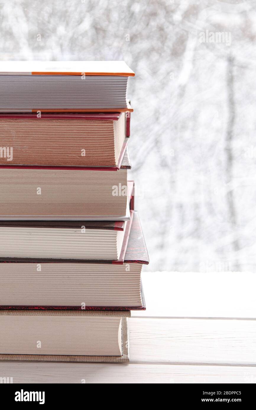 Book stack on wood desk and blurred bookshelf in the library room ...