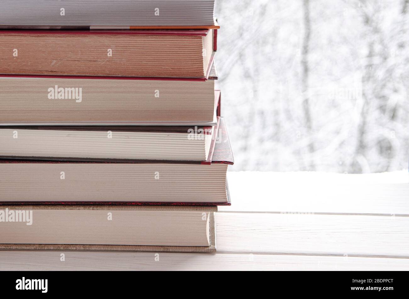 Book stack on wood desk and blurred bookshelf in the library room ...