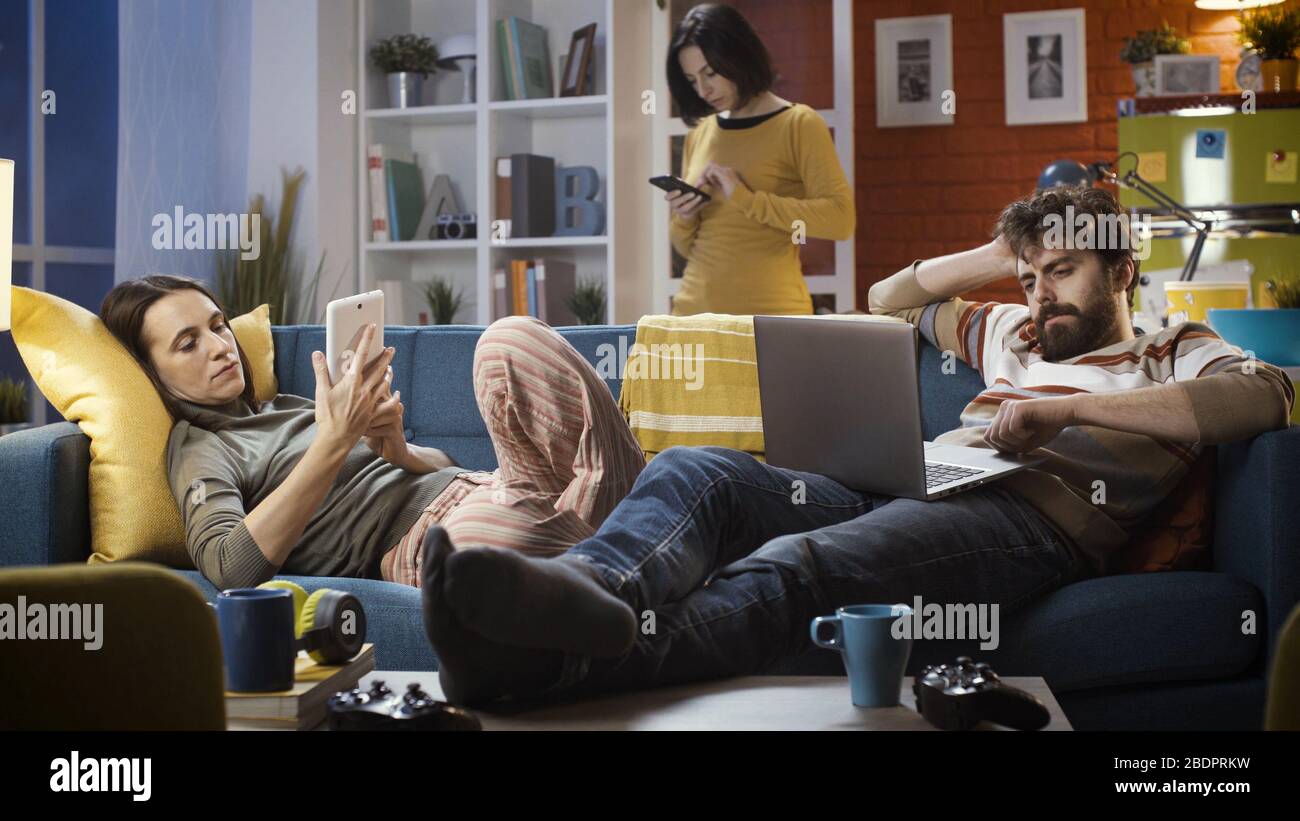 Friends connecting with their devices at home and ignoring each other ...