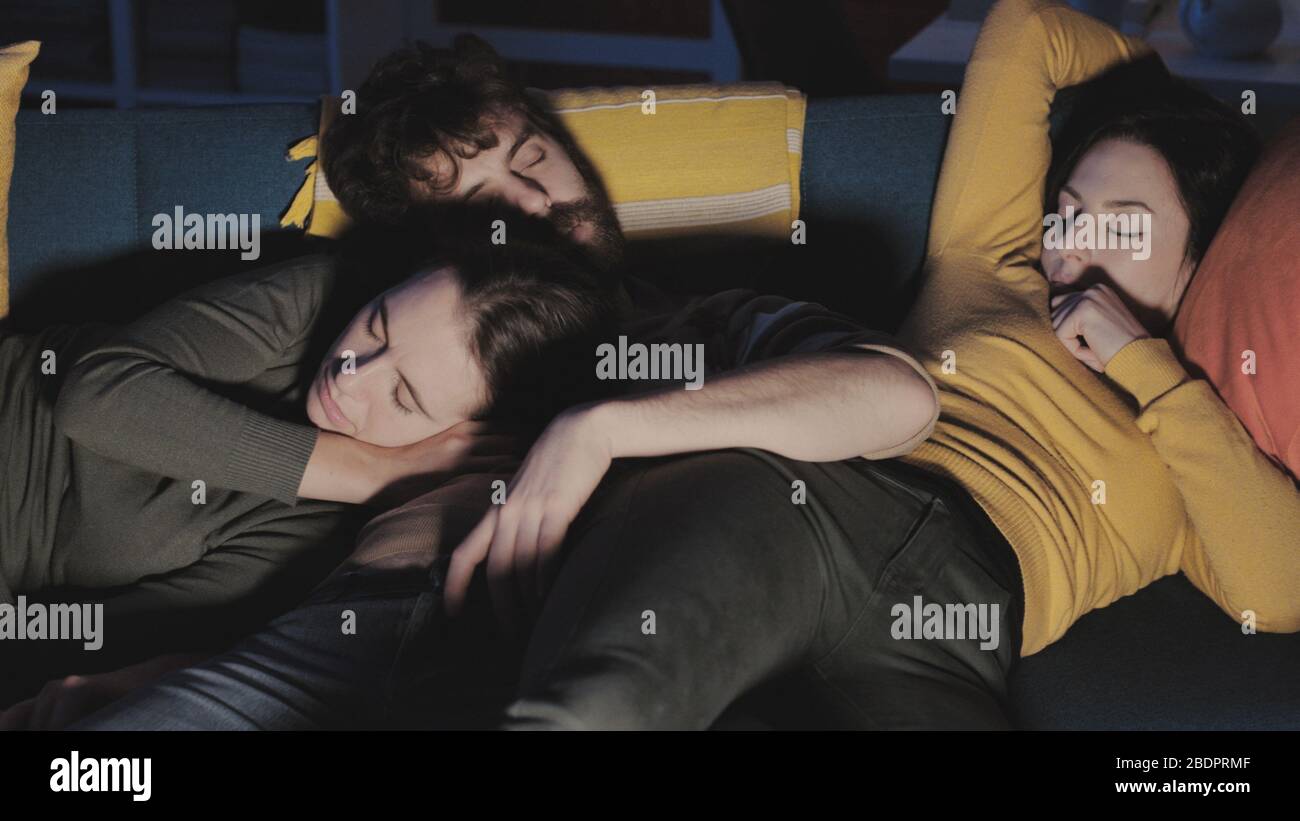 Tired friends lying down on the sofa at home and falling asleep ...