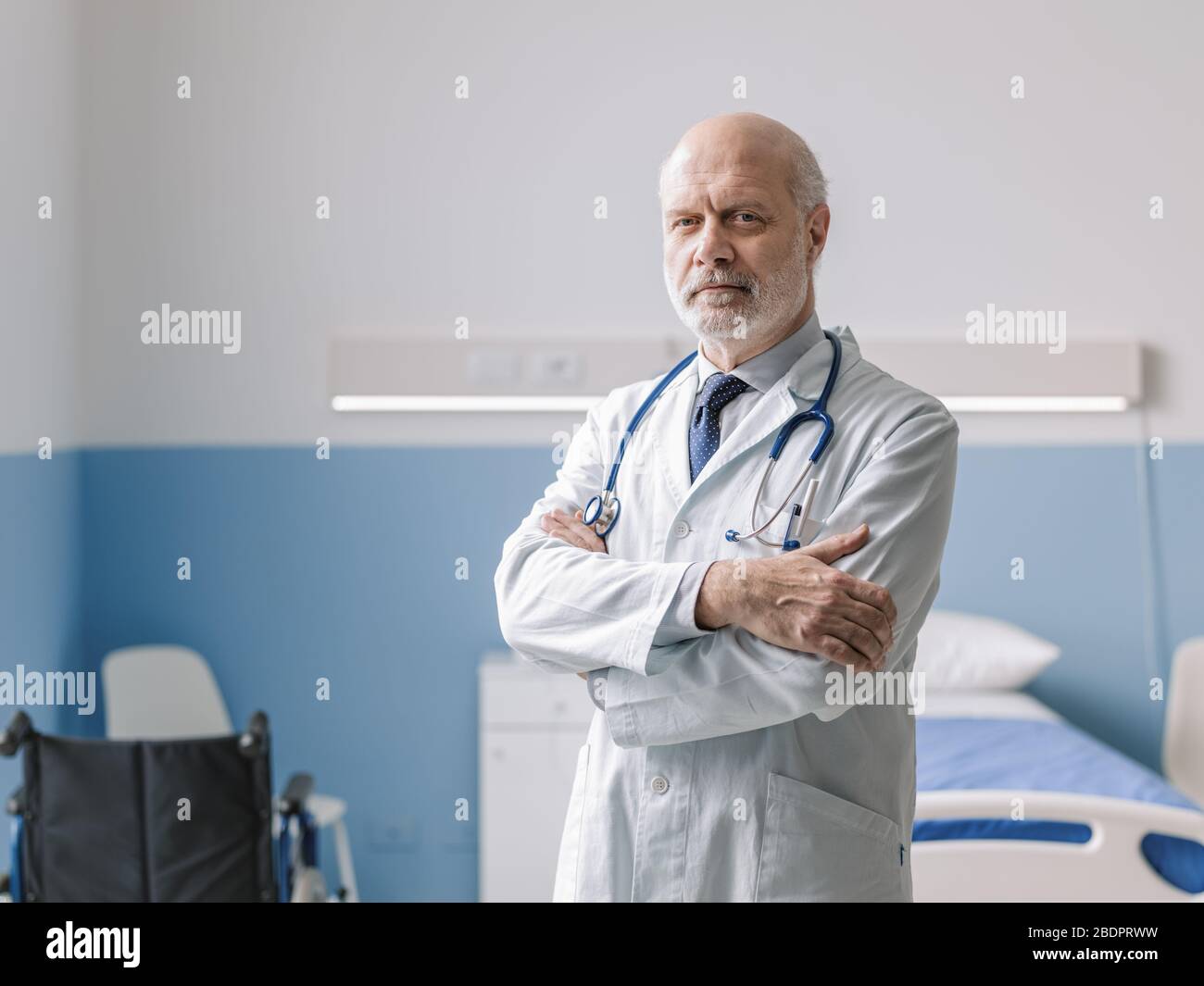 Professional doctor standing next to a hospital bed and posing with ...