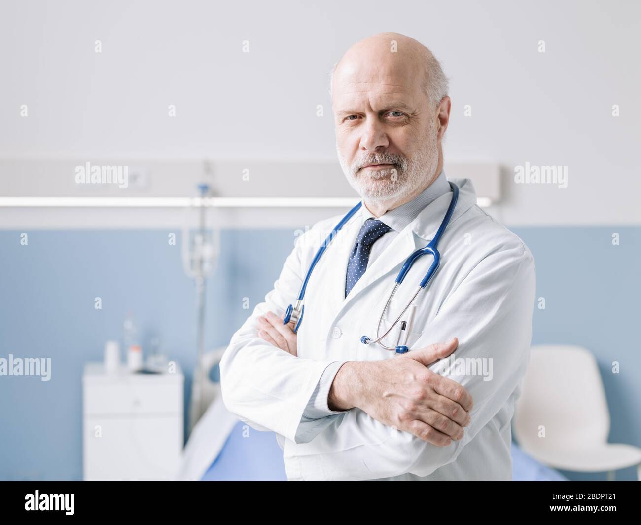 Professional doctor standing next to a hospital bed and posing with ...