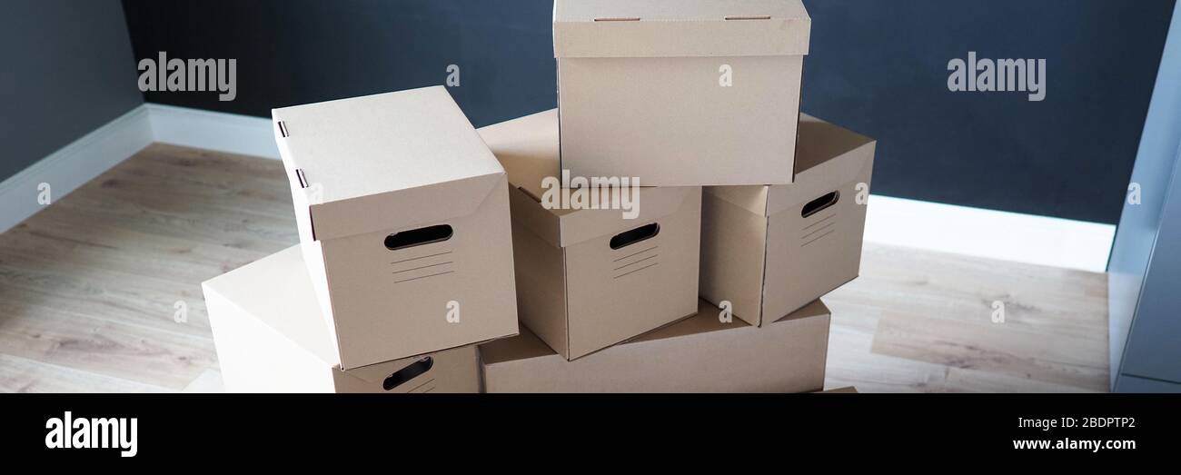 Pile of carton boxes standing in the middle of empty room in new house ...