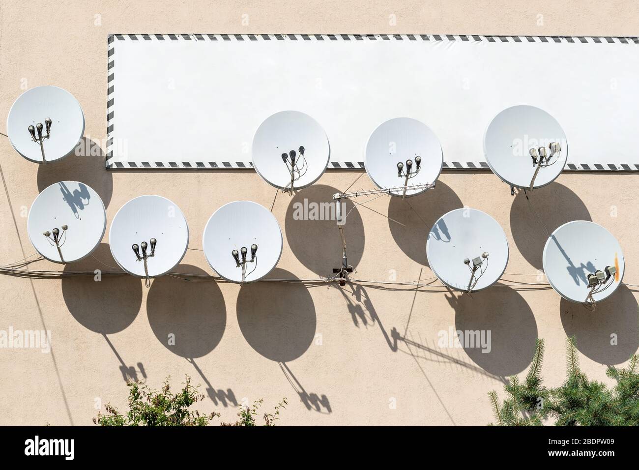 Many satellite dish antenna hanged on building wall with big white ...
