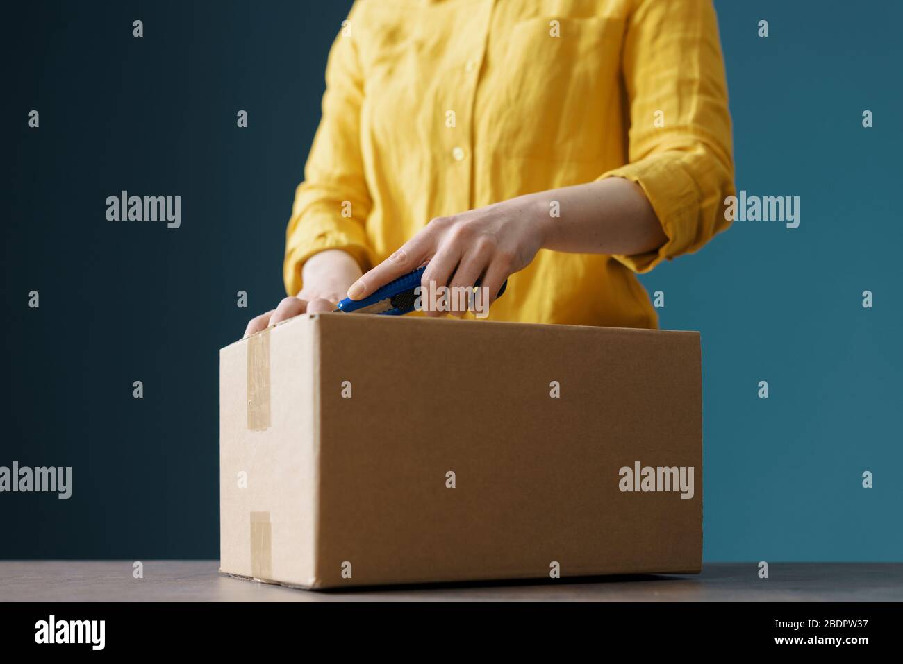 Woman opening a delivery box using a cutter Stock Photo - Alamy