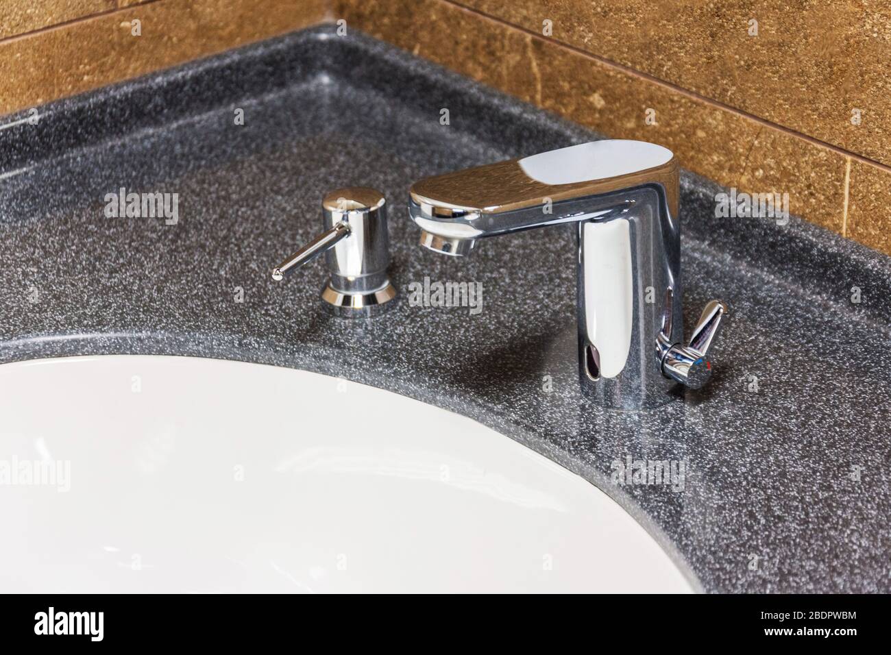 White sink in brown marble countertop with chrome shiny faucet and ...