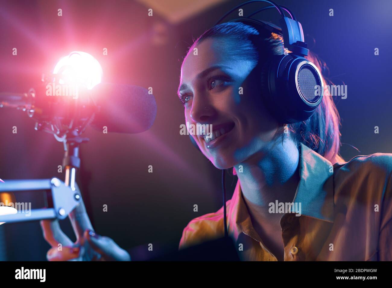 Young smiling host at the radio broadcasting station, communication and ...