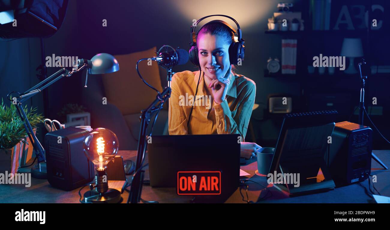 Young smiling radio host talking into a microphone and broadcasting at ...