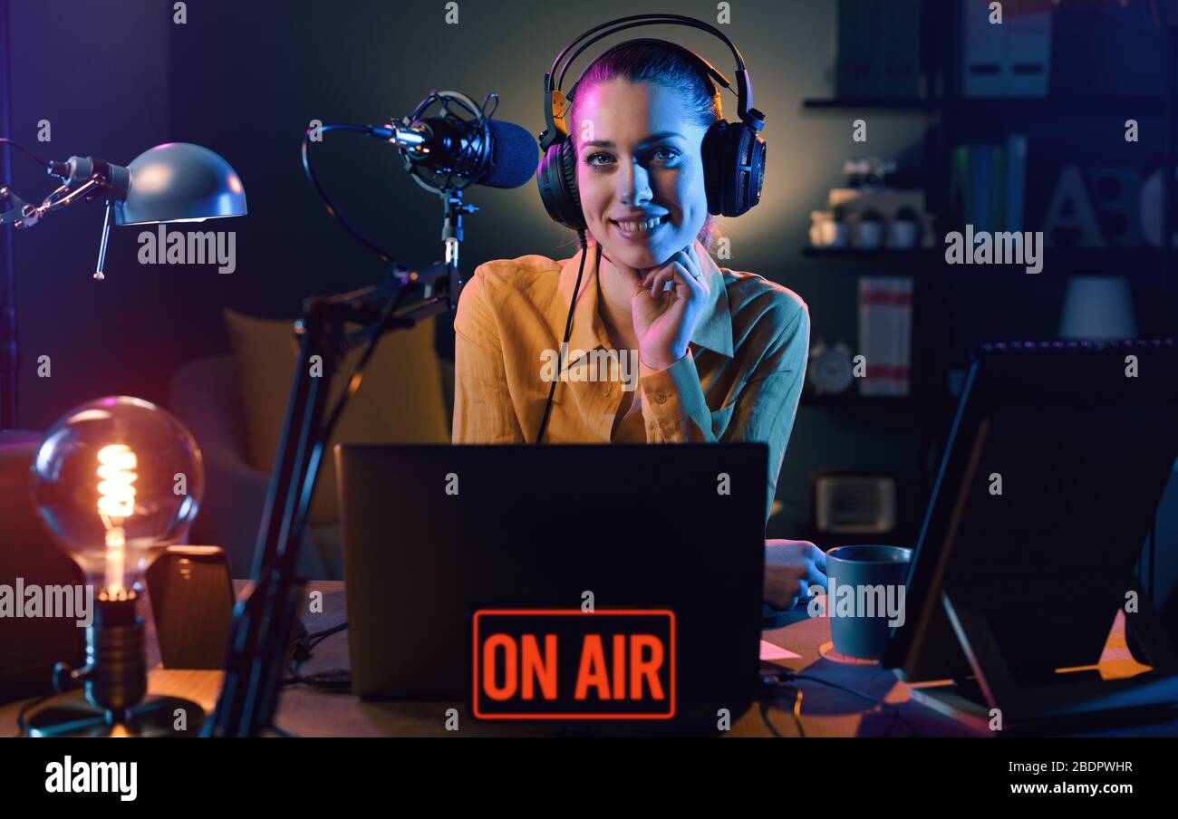 Young smiling radio host talking into a microphone and broadcasting at ...