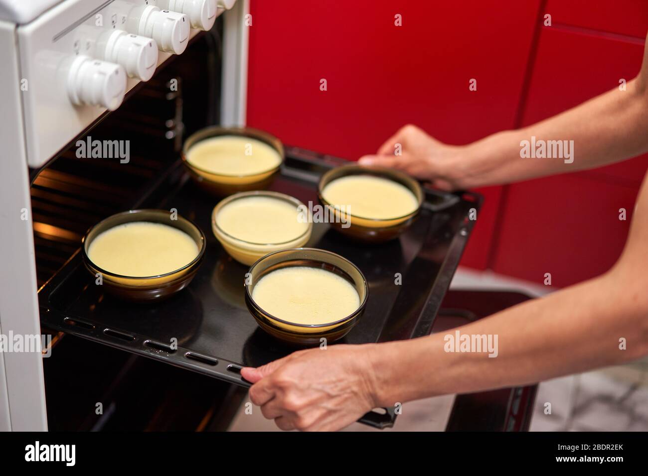 Inserting tray with creme brulee bowls into the oven Stock Photo - Alamy
