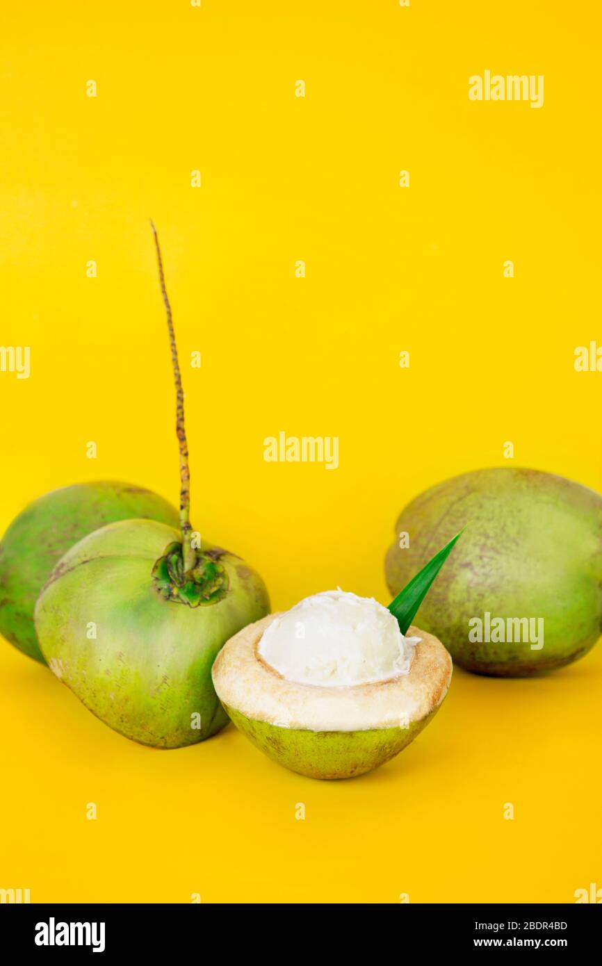 Four Coconuts with yellow background Stock Photo - Alamy