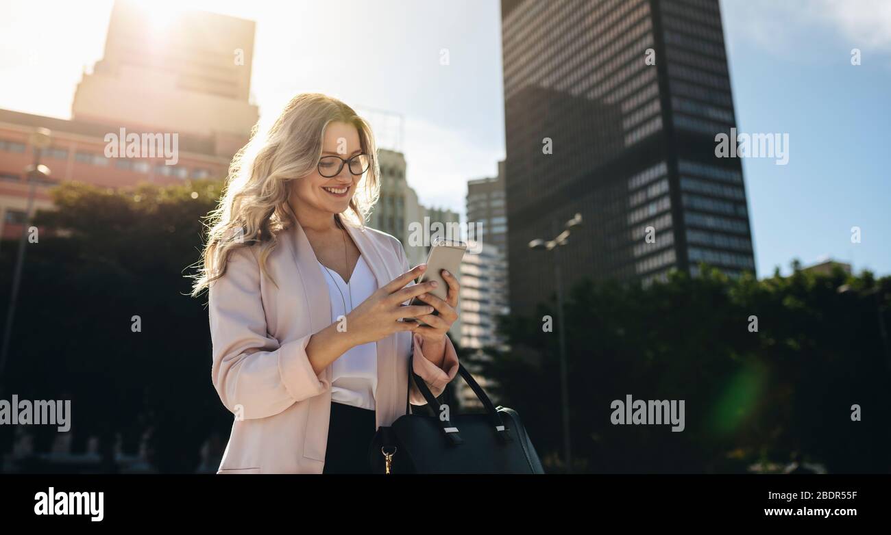 Urban realtor walking in the city using her mobile phone. businesswoman ...