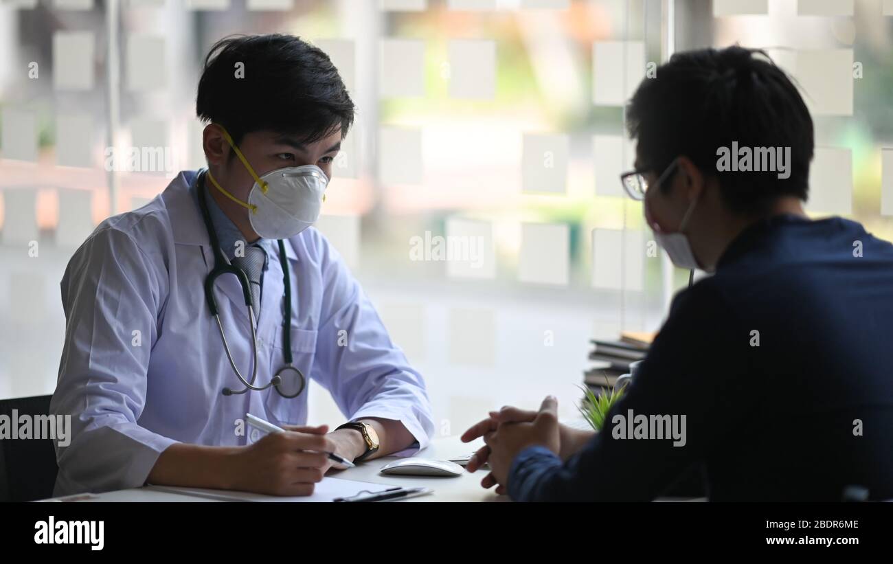 Photo of young smart doctor giving an advice to his patient while ...
