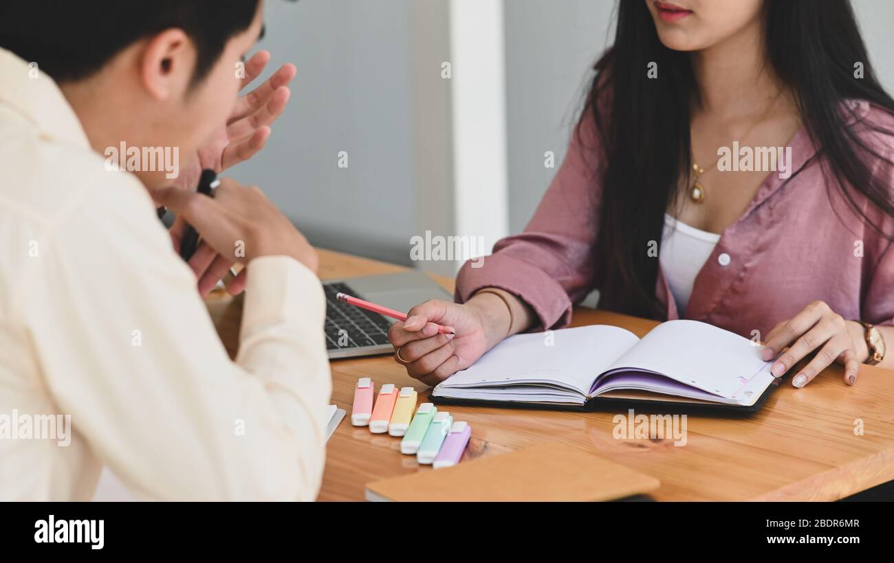Photo of young smart man training/coaching/teaching his new colleague ...