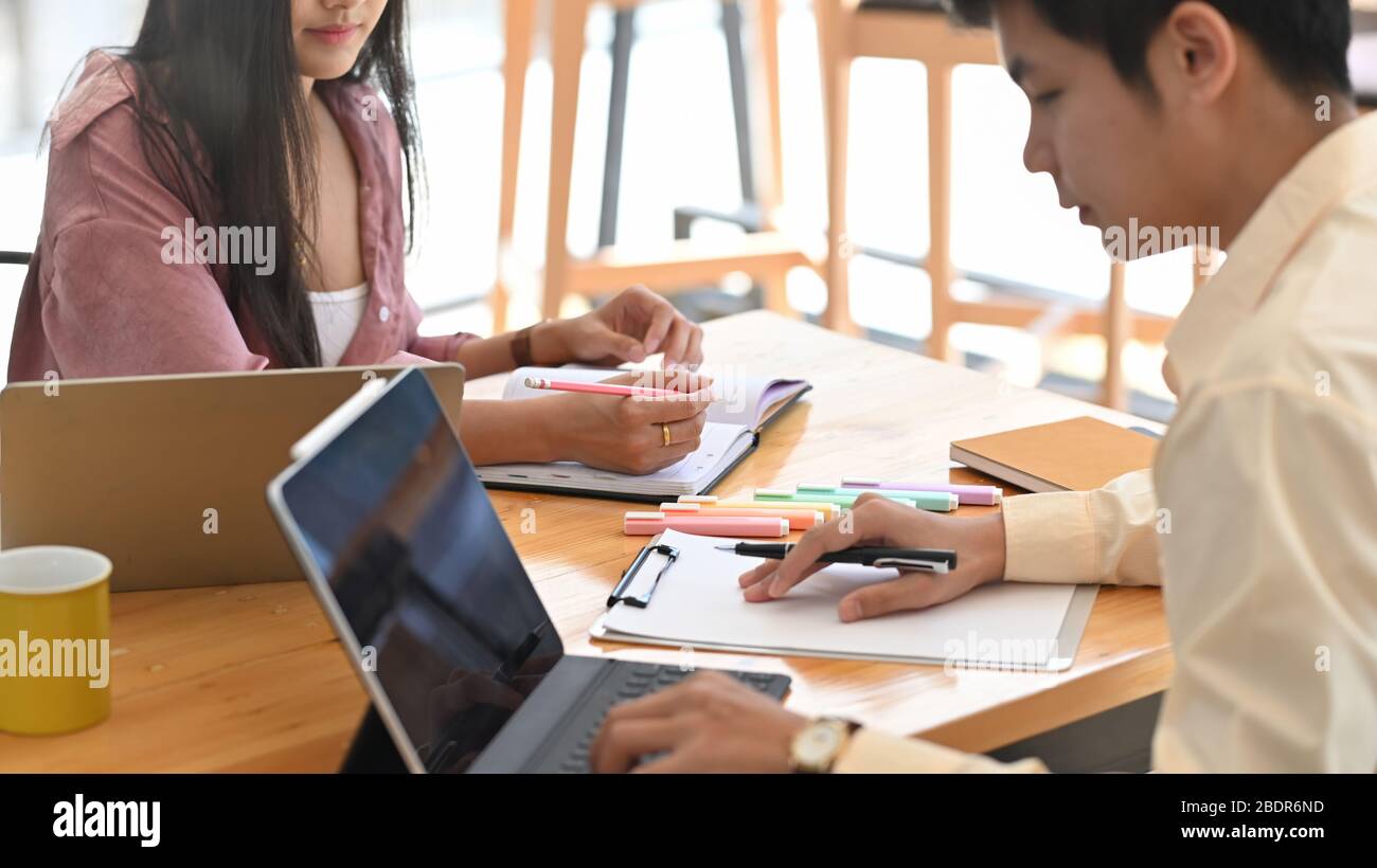 Photo of young smart man training/coaching/teaching his new colleague ...