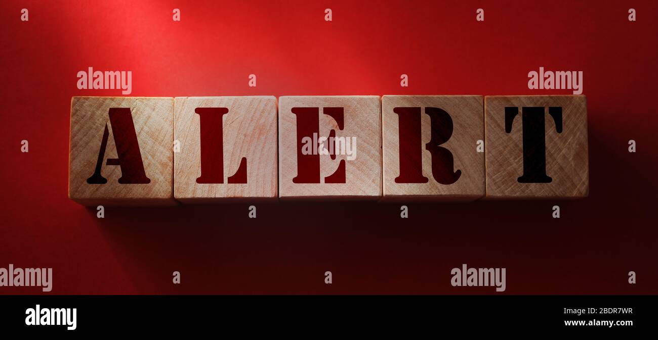 ALERT word on a wooden cubes on red background. Prevention, attention ...