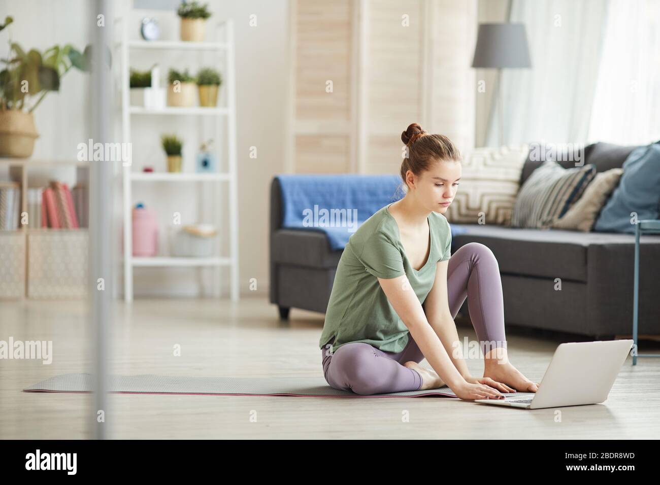Young beautiful woman sitting on the floor in front of laptop and ...