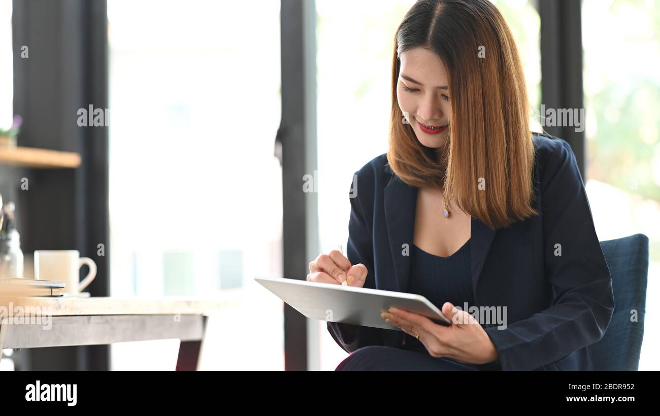 Executive woman holding a computer tablet and stylus pen in her hands ...
