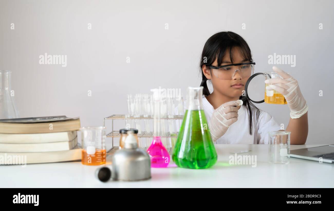 Photo of adorable schoolgirl looking through a magnifying glass while ...