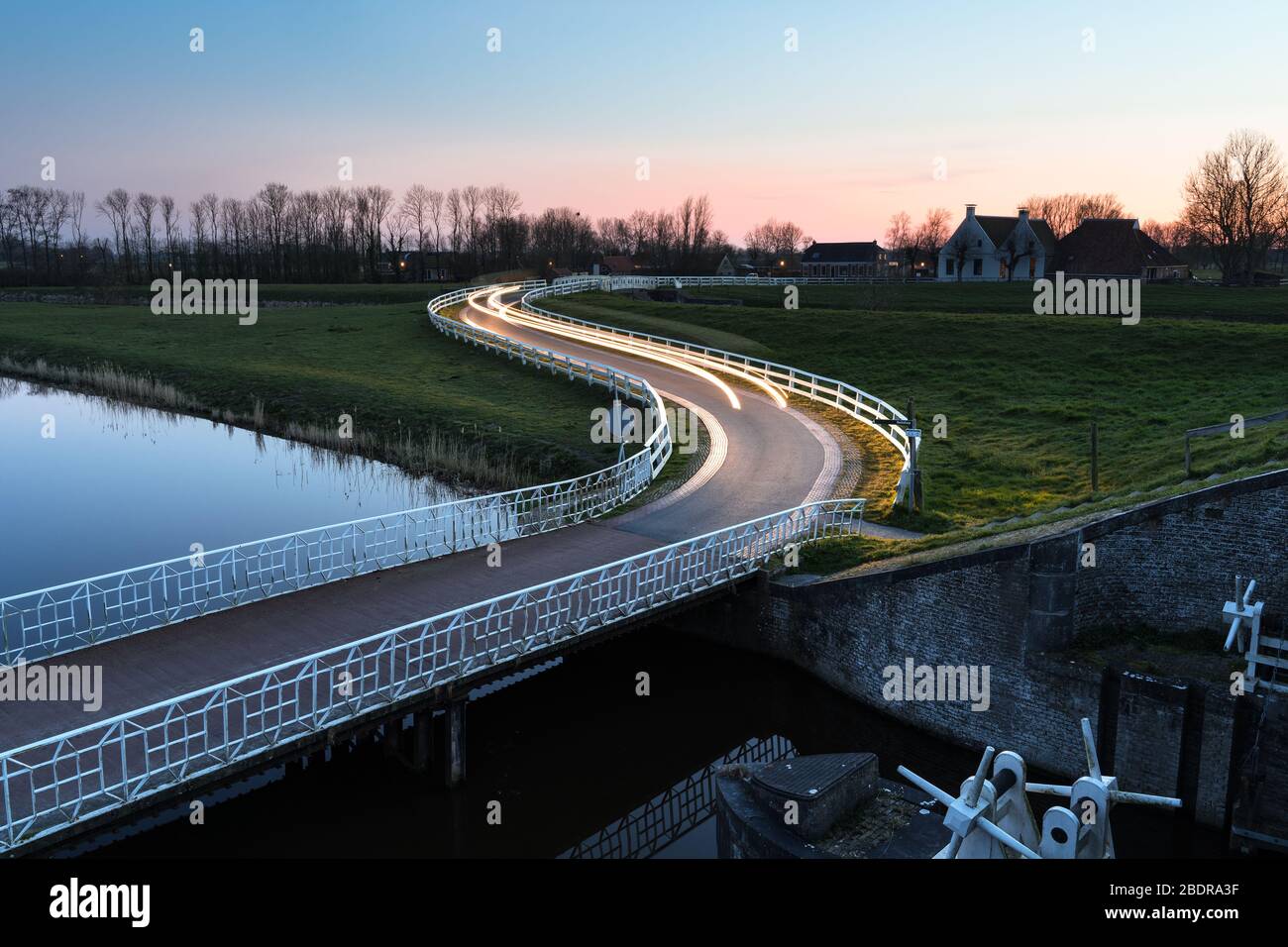 Curved Asphalt country road in dutch countryside with white fence ...
