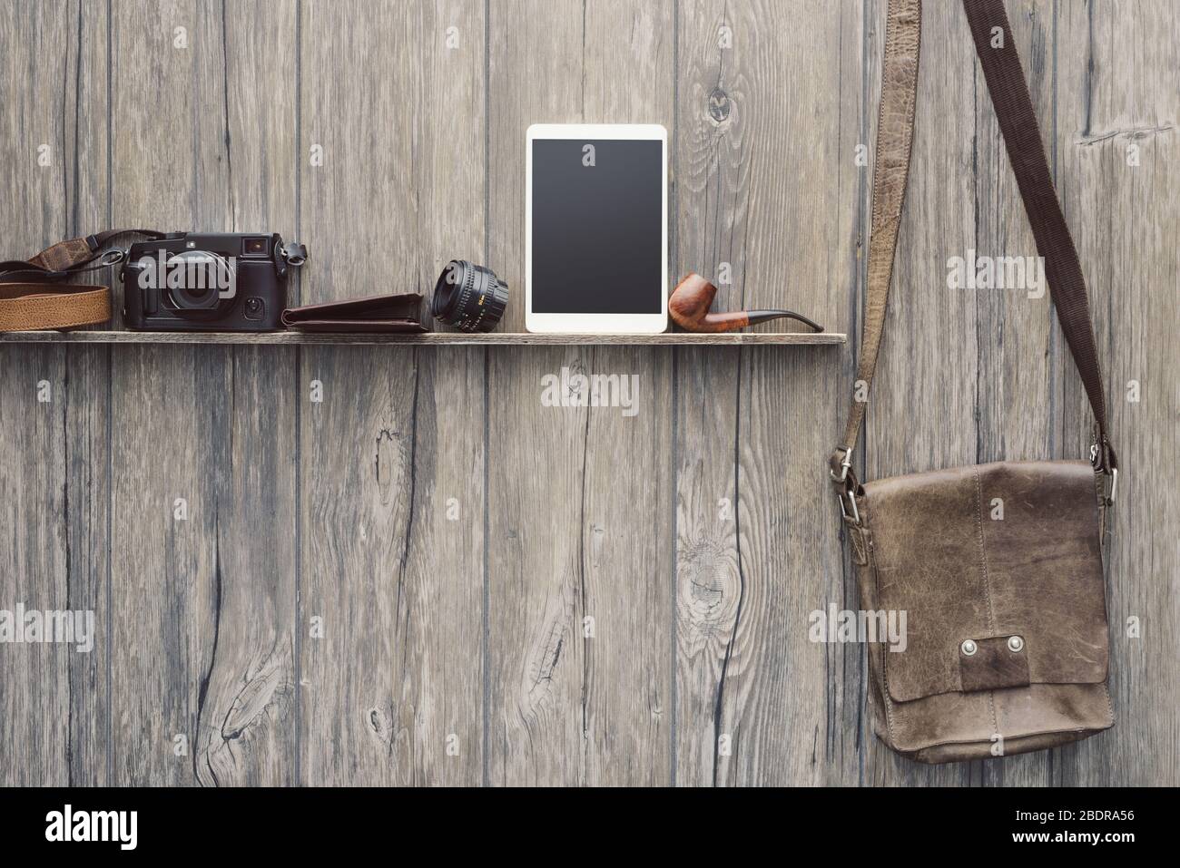 Shelf with a camera, tablet, a pipe and a leather bag hanging on the ...