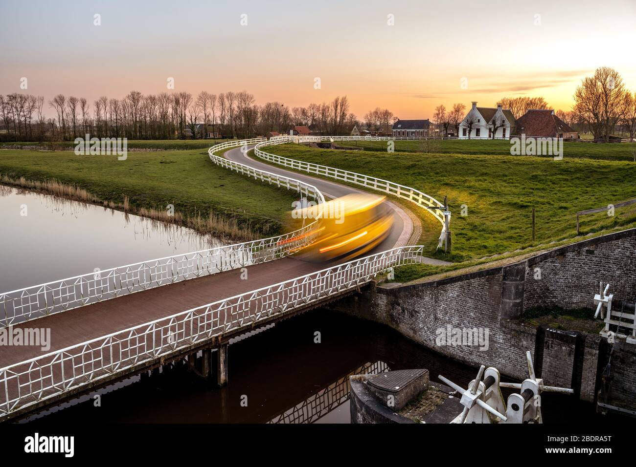 Curved Asphalt country road in dutch countryside with white fence ...