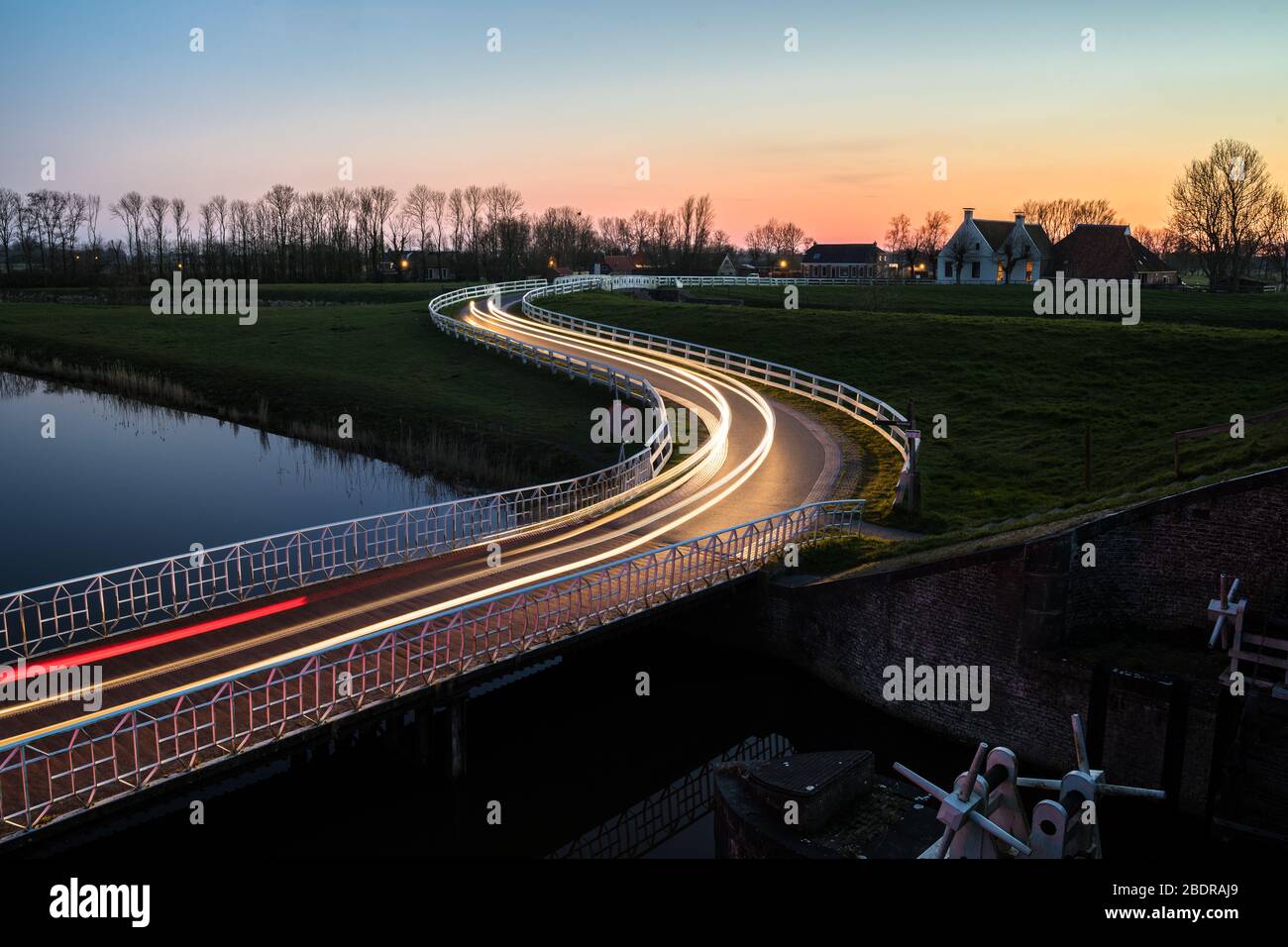 Curved Asphalt country road in dutch countryside with white fence ...