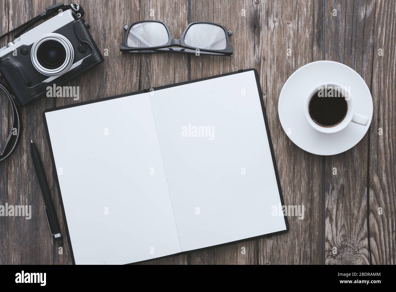 Blank open notebook, camera and glasses on a hipster wooden desktop ...