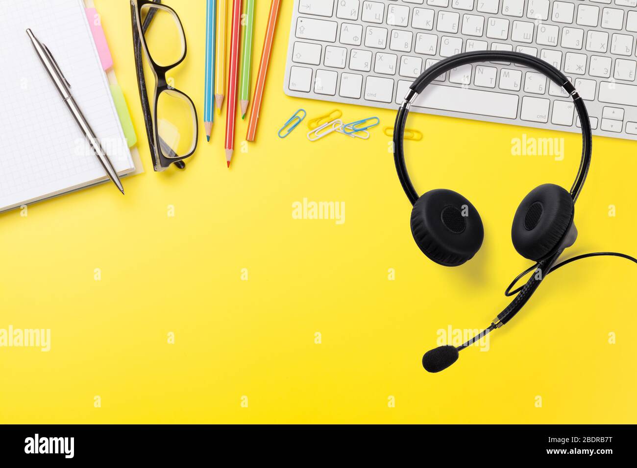 Office yellow workplace backdrop with supplies, headset and computer ...