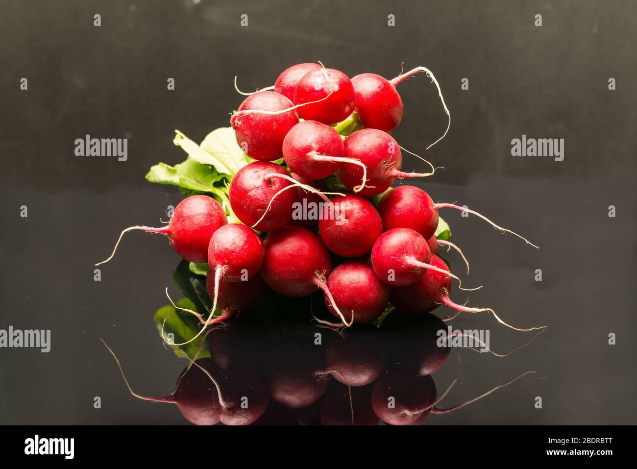 Fresh radishes against black background with reflection Stock Photo - Alamy
