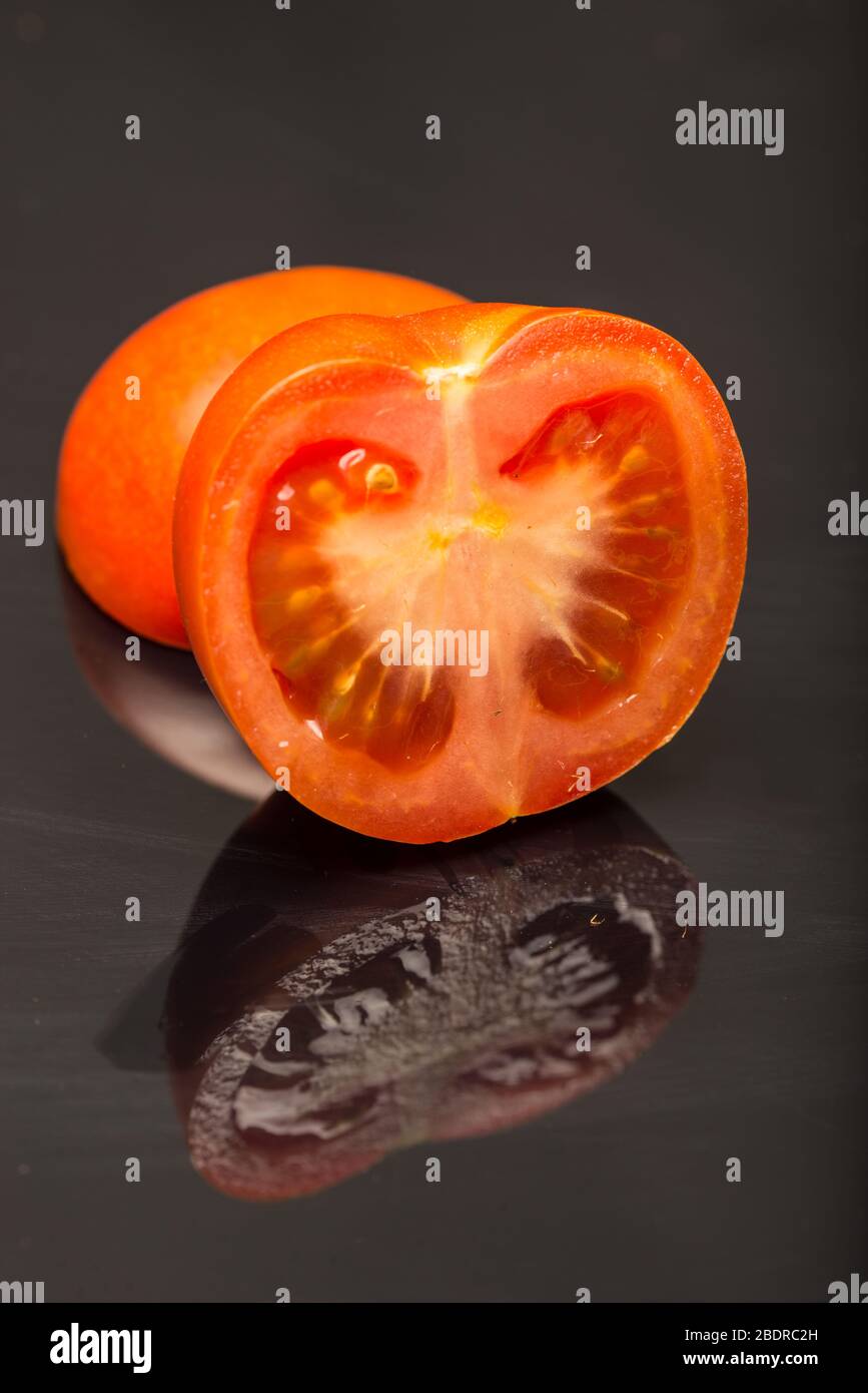 Sliced fresh tomato against black background with reflection Stock ...