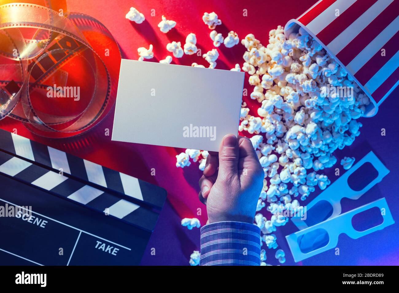 Hand holding a blank cinema promo card or ticket; popcorn, filmstrip ...