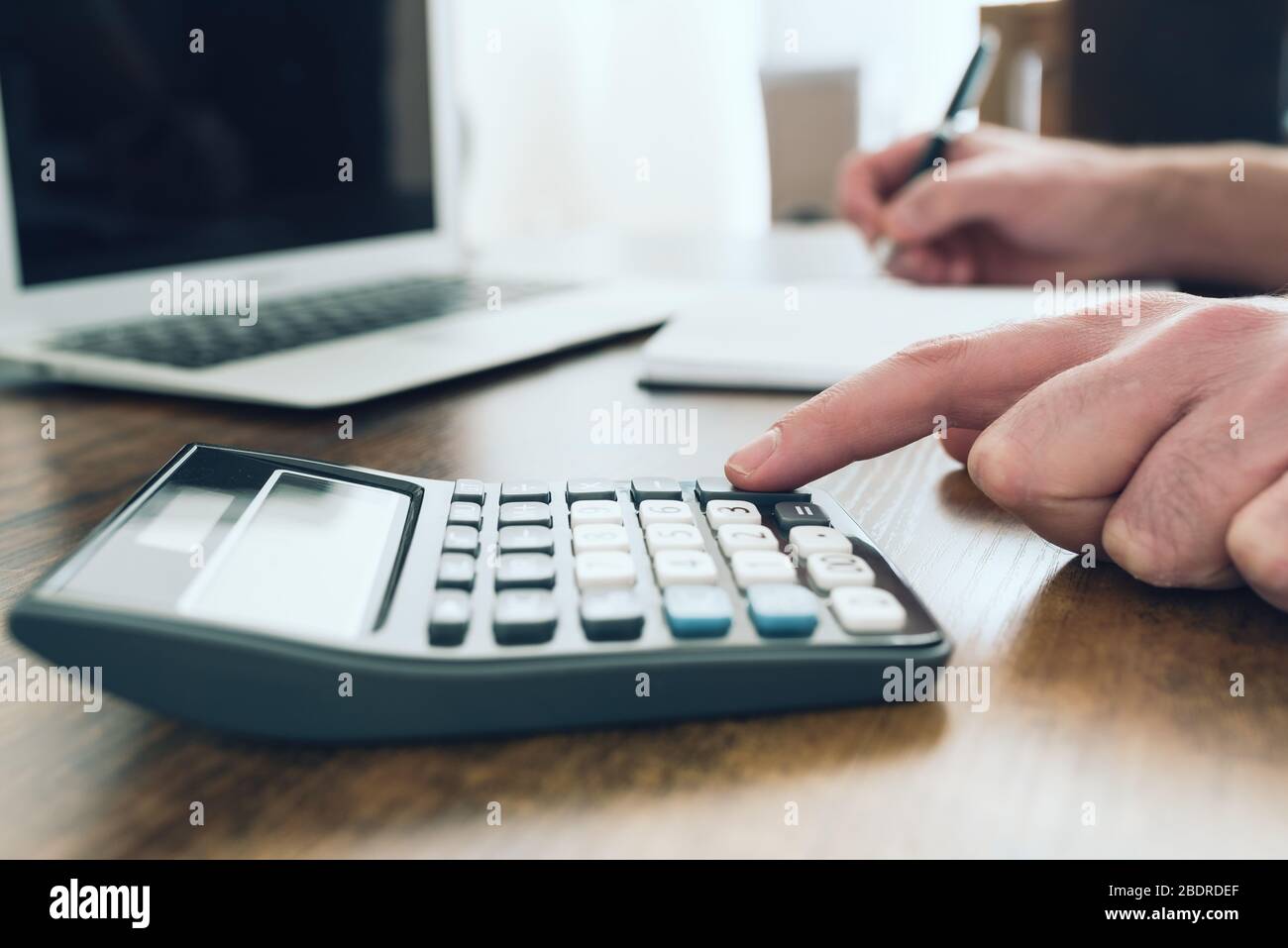 close-up shot of person using pocket calculator while taking notes on ...