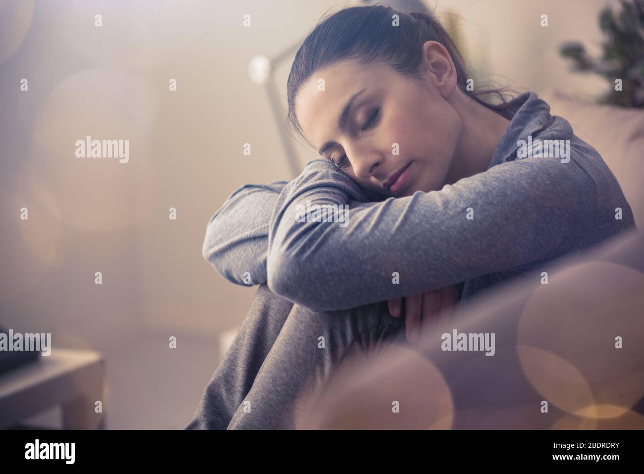 Sad suffering woman curling on the couch at home she is depressed and ...