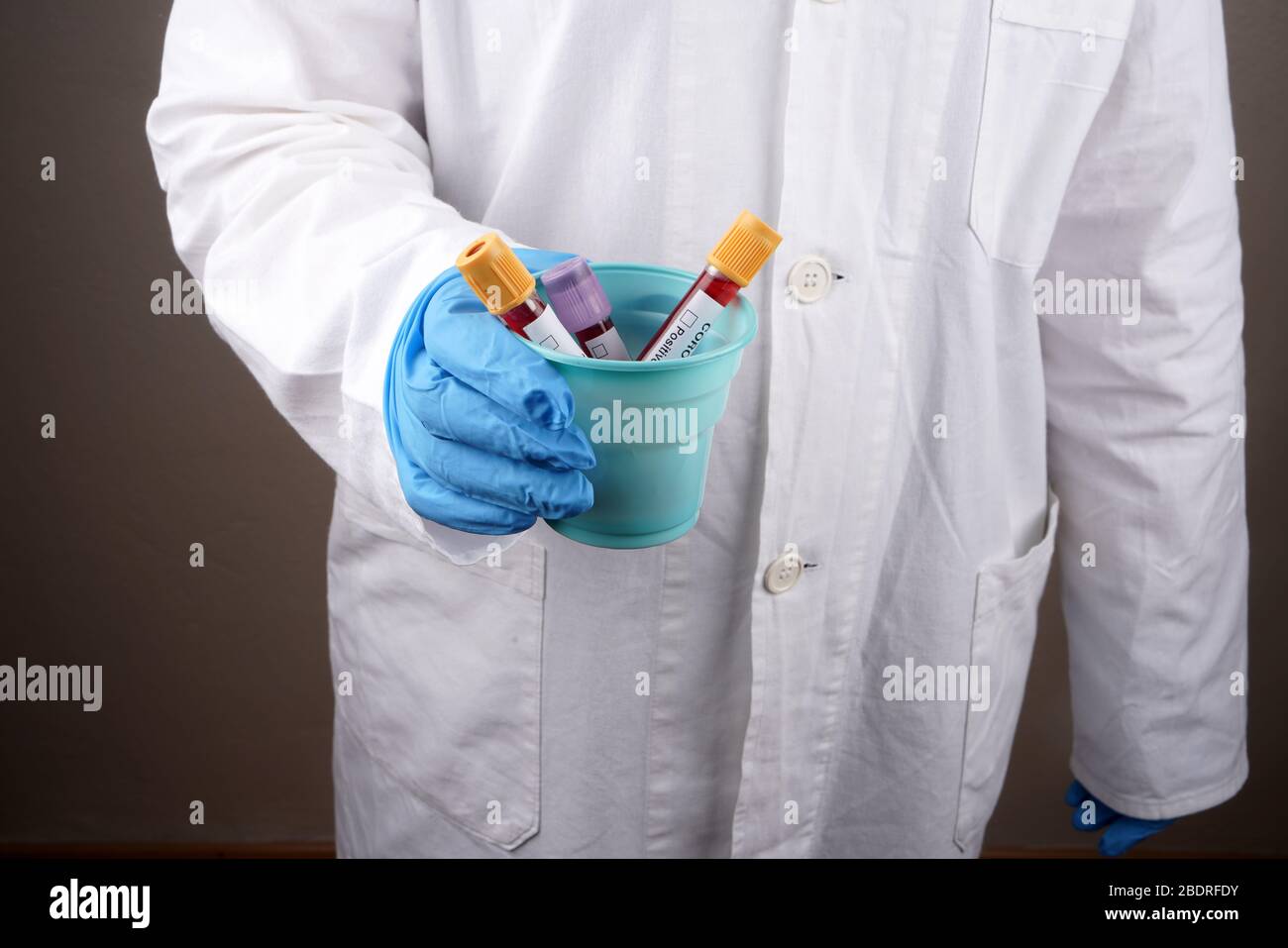 Doctor holding blood tubes in plastic cup Stock Photo - Alamy