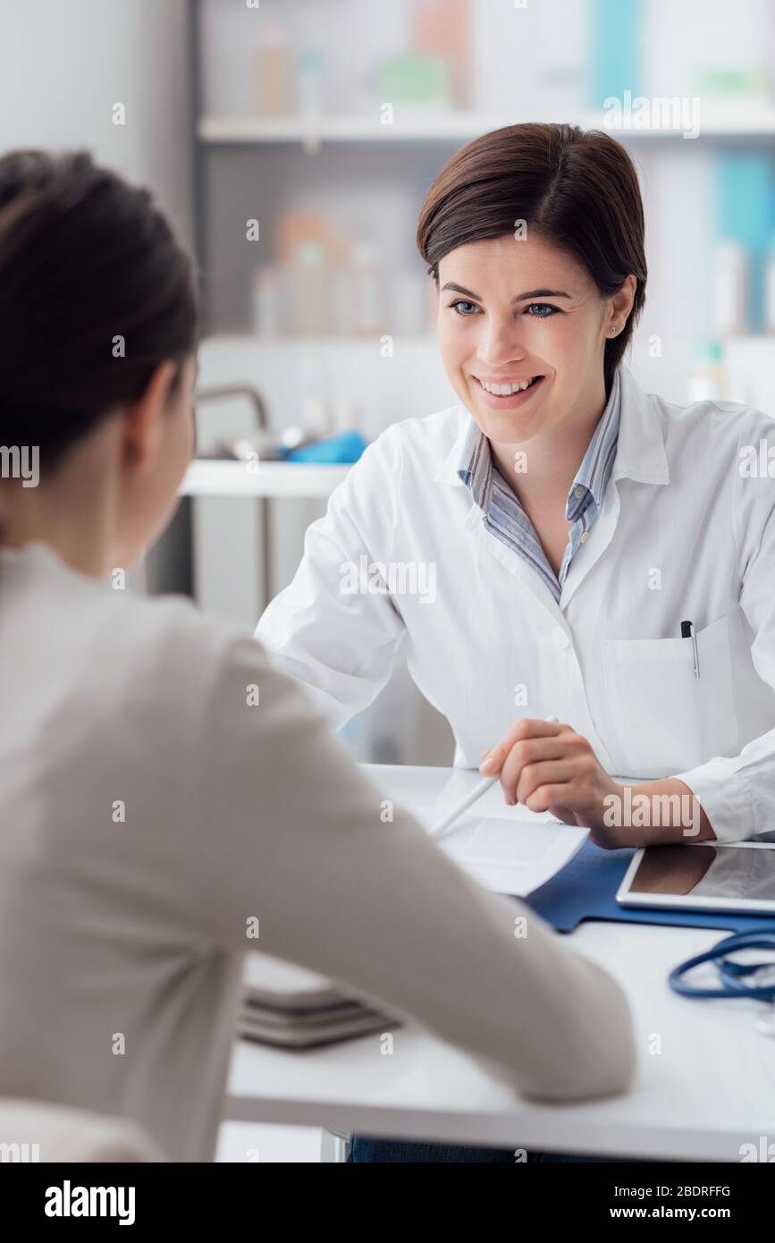 Female doctor giving a consultation to a patient and explaining medical ...