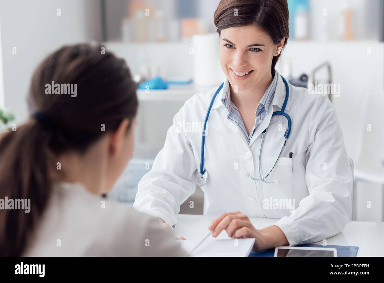 Female doctor giving a consultation to a patient and explaining medical ...