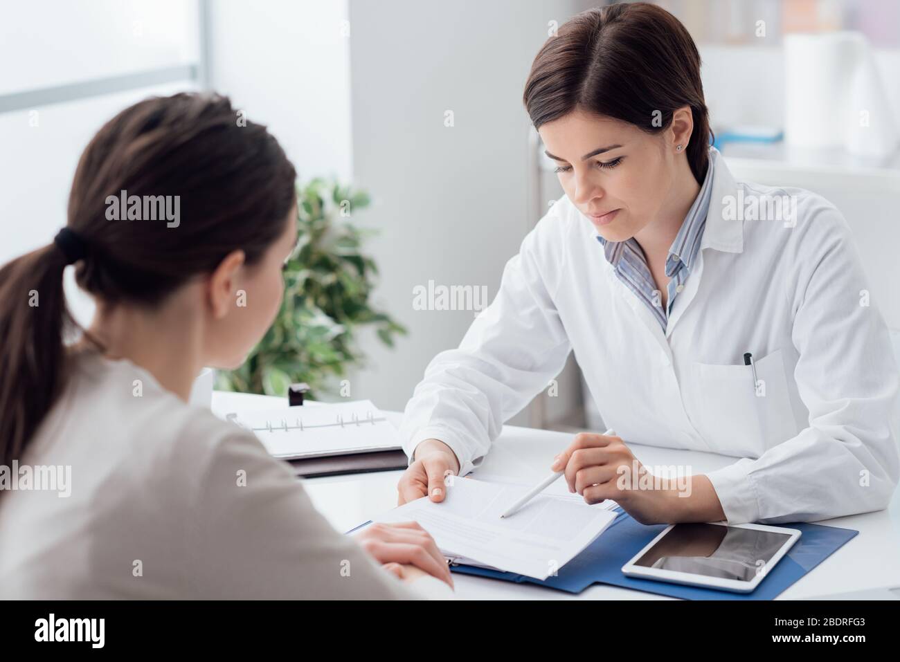 Female doctor giving a consultation to a patient and explaining medical ...